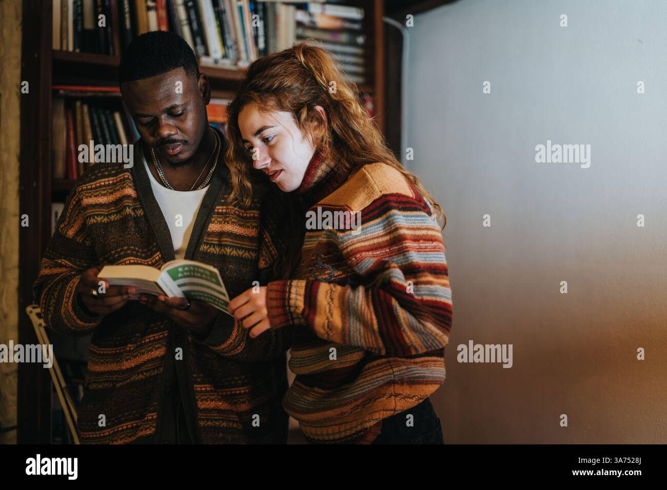 Two friends reading a book together in a cozy library environment Stock ...
