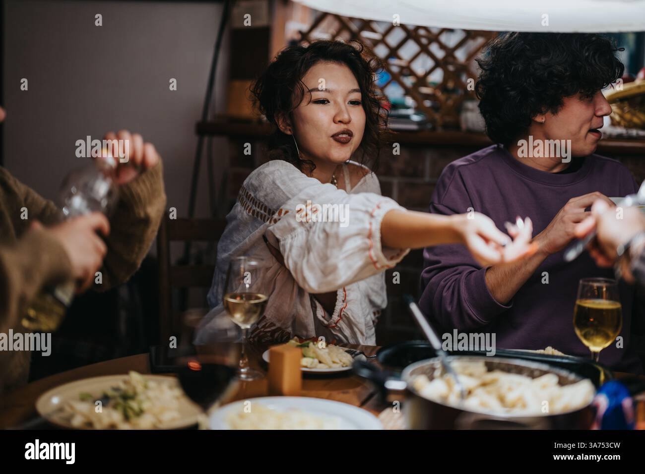Friends enjoying dinner together around a table with food and drinks ...