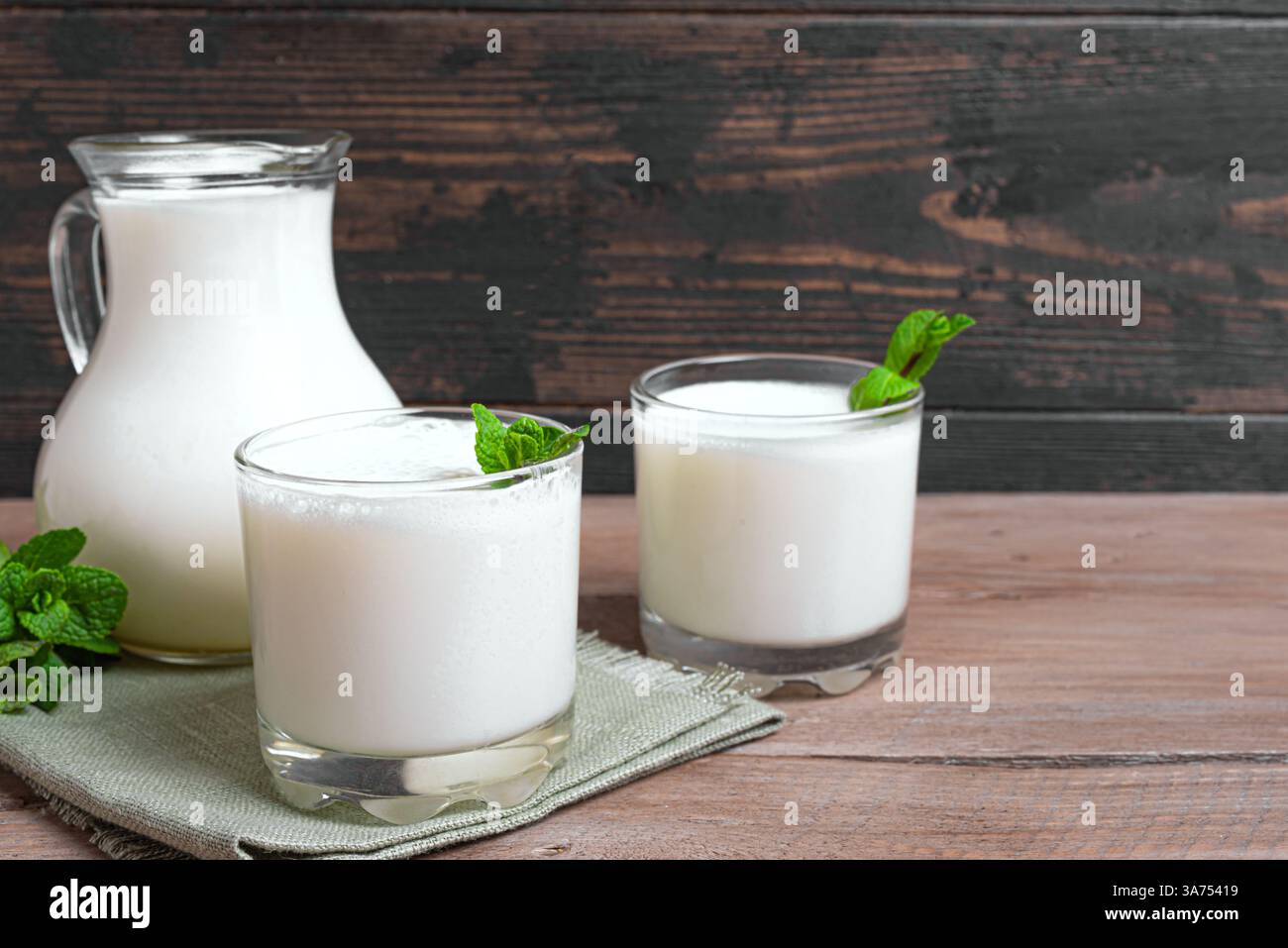 Turkish traditional drink ayran, kefir or buttermilk in glasses and jug ...