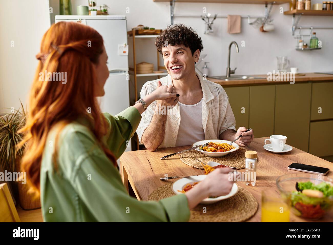 In a chic kitchen, a young couple enjoys a meal, sharing joy and ...