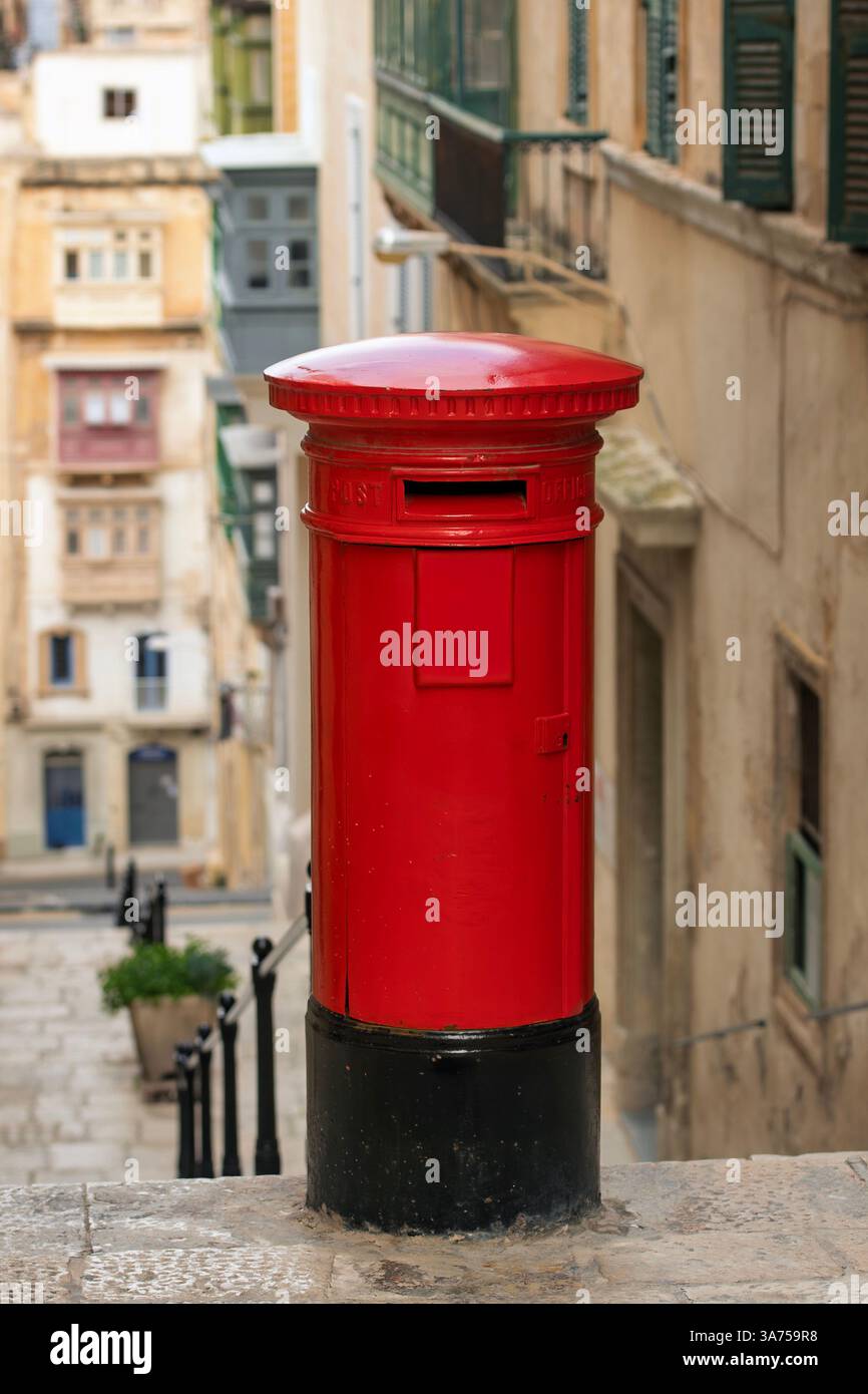 A classic British red post box with "POST OFFICE" inscription, actively ...