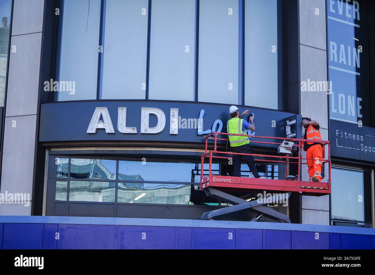 London, UK 26 March 2025. Workers prepare the signage for the new Aldi ...