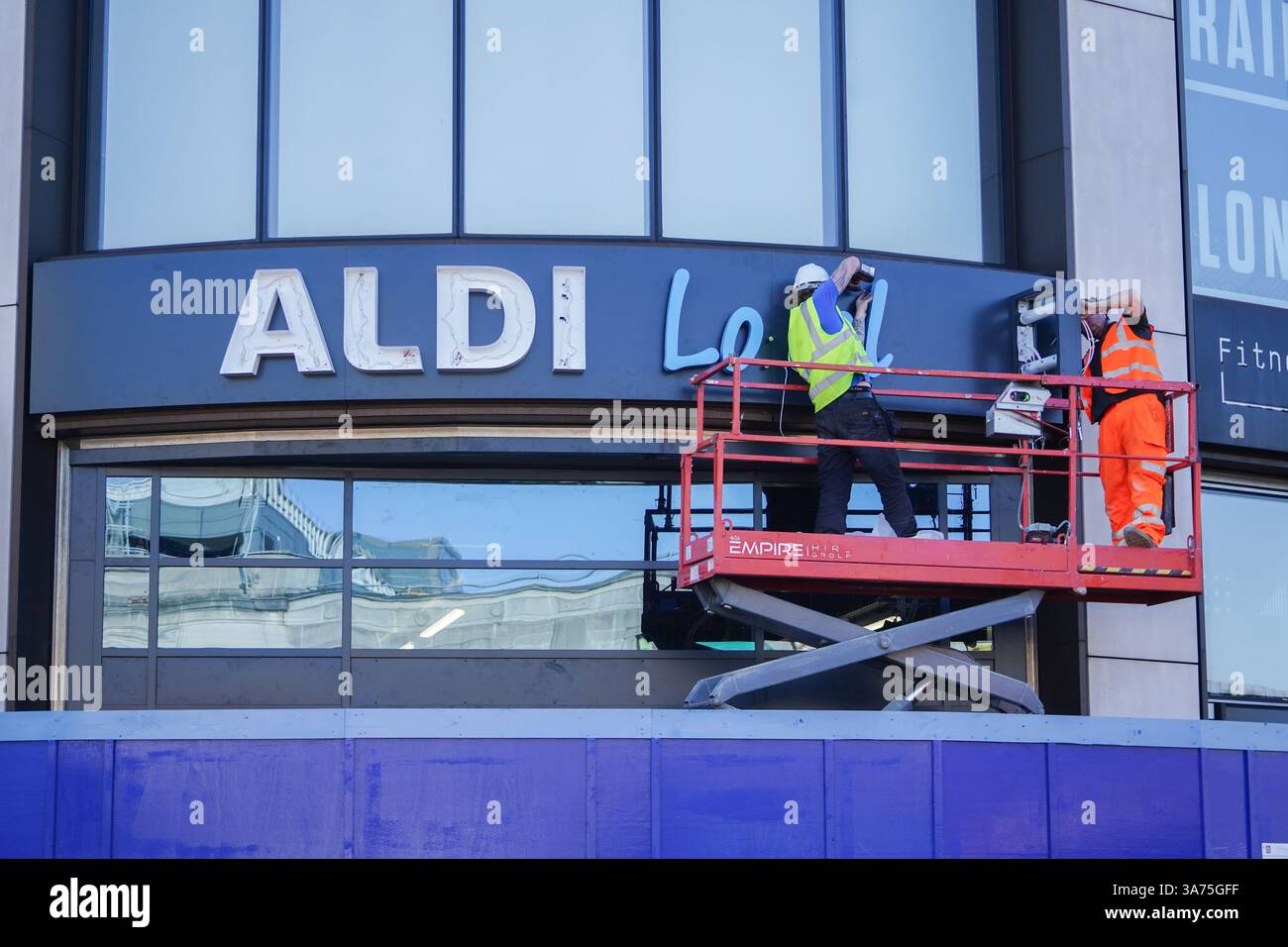 London, UK 26 March 2025. Workers prepare the signage for the new Aldi ...