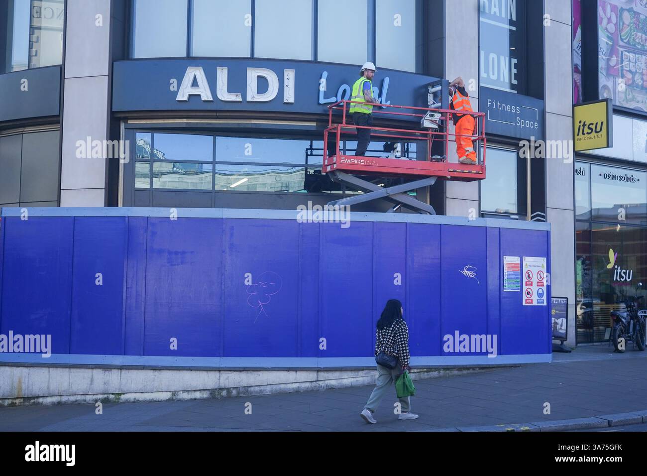 London, UK 26 March 2025. Workers prepare the signage for the new Aldi ...