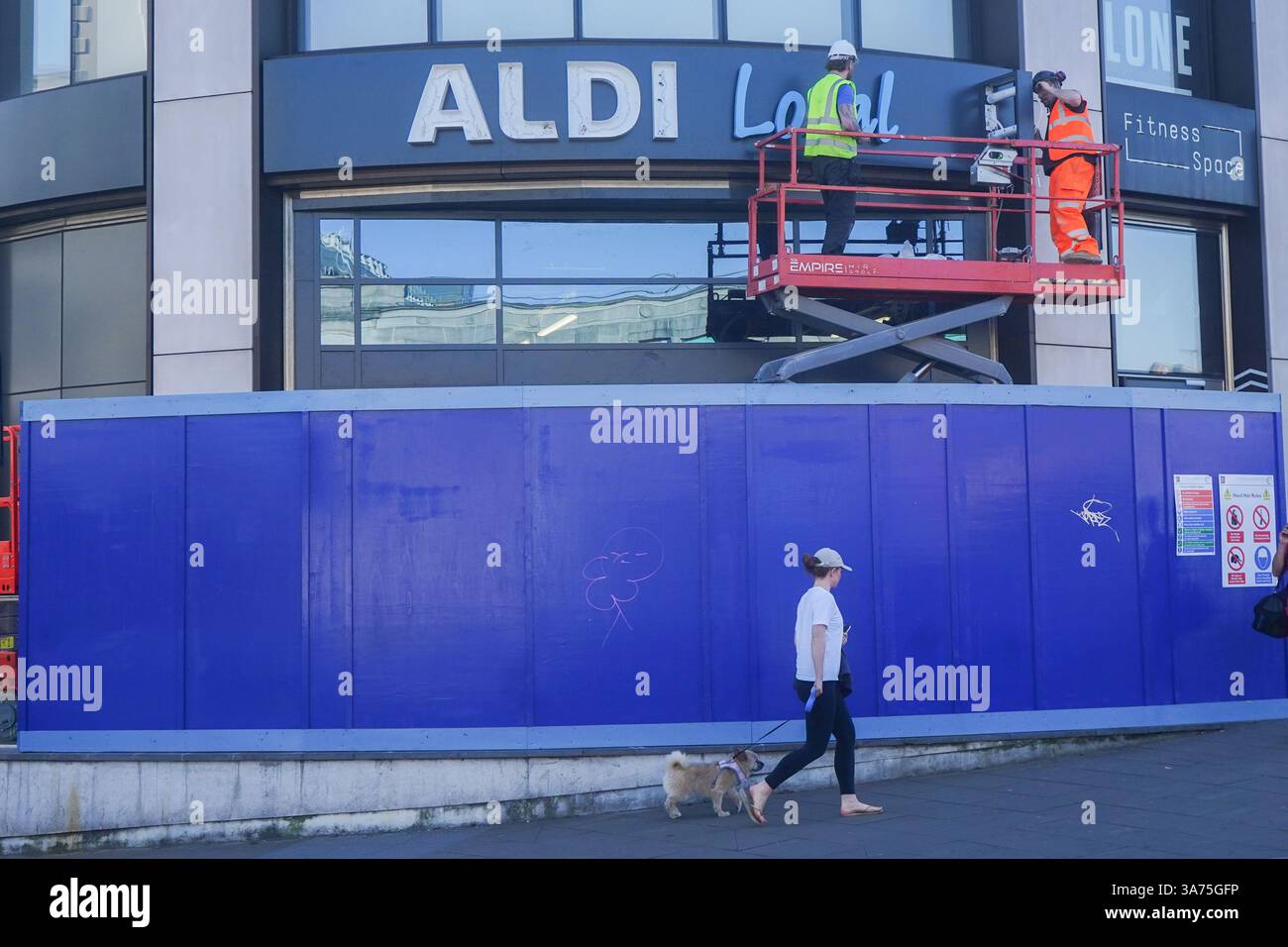 London, UK 26 March 2025. Workers prepare the signage for the new Aldi ...