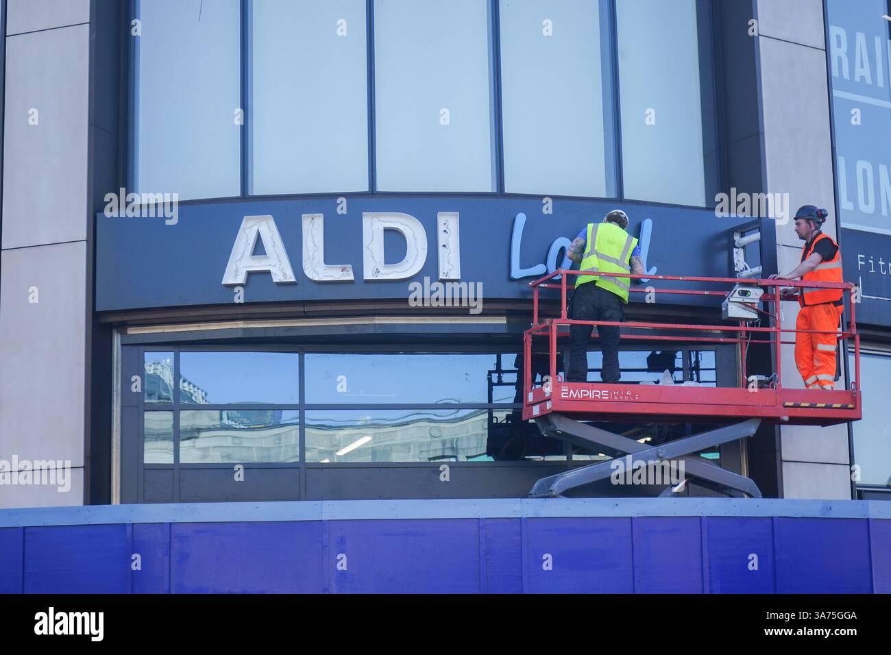 London, UK 26 March 2025. Workers prepare the signage for the new Aldi ...