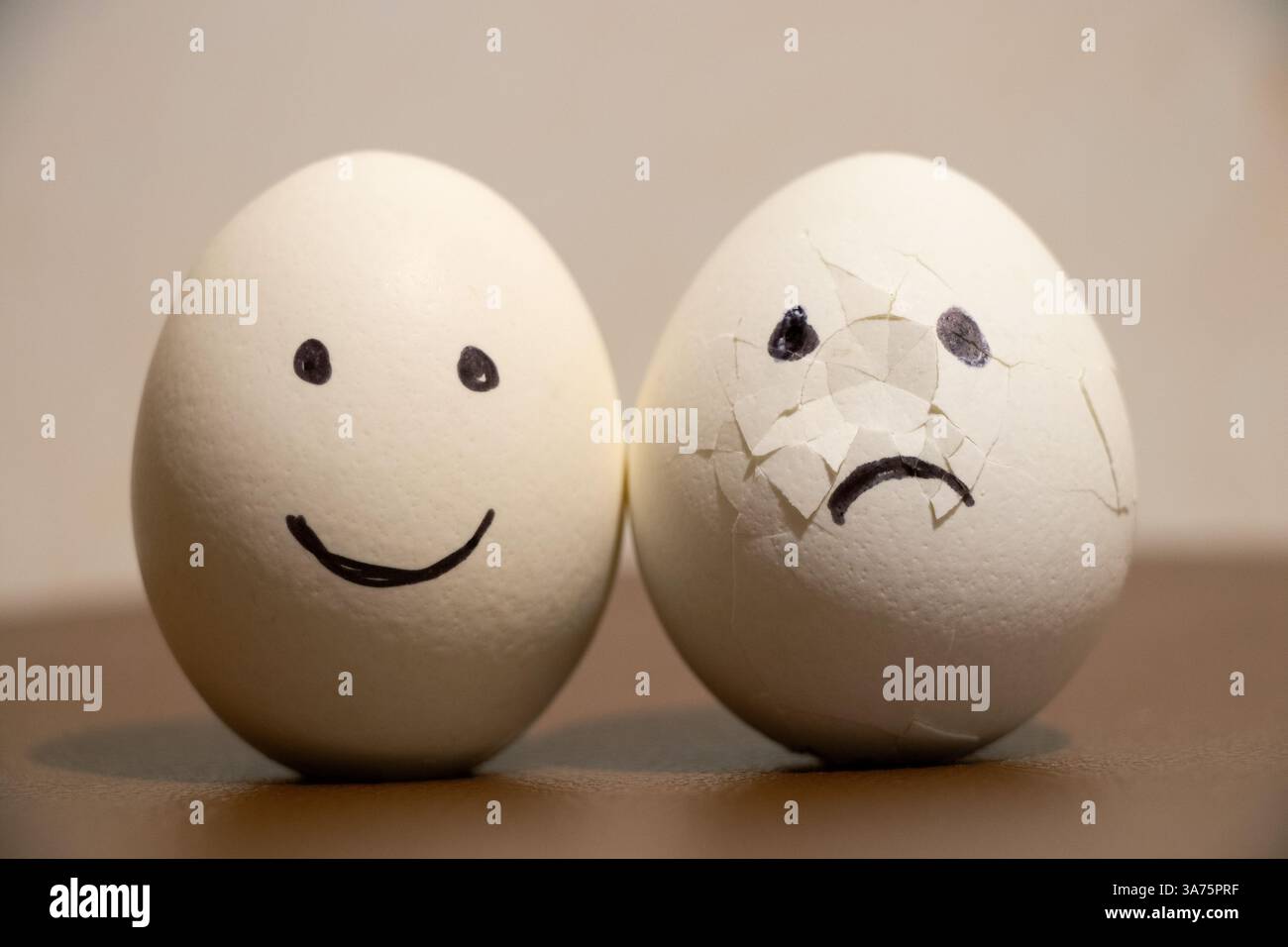 Two chicken eggs, one with joy, and the second broken with sad emotions ...