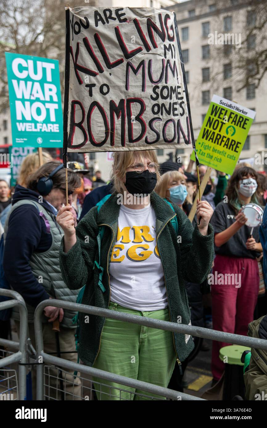 London, UK. 26th Mar, 2025. An activist holds a banner above her head ...
