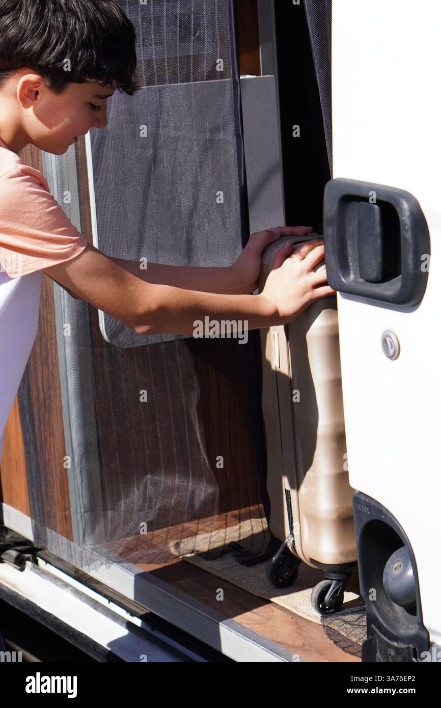 Vacation and travel concept. smiling preteen boy loading his suitcase ...