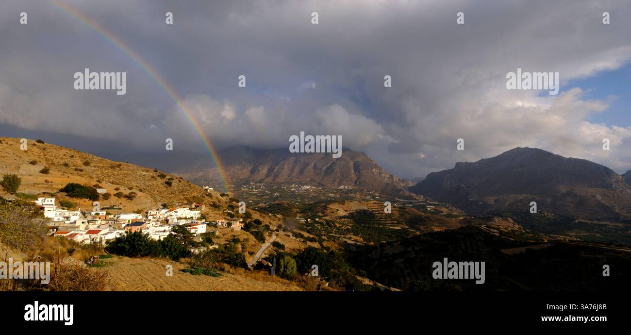 After a brief rain shower, a vibrant rainbow arcs over a small village ...