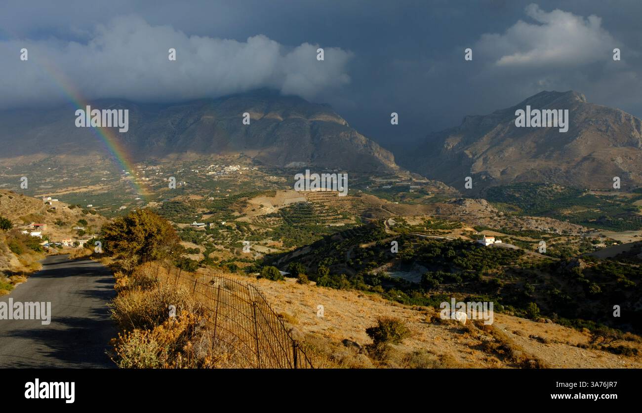 After a brief rain shower, a vibrant rainbow arcs over a small village ...