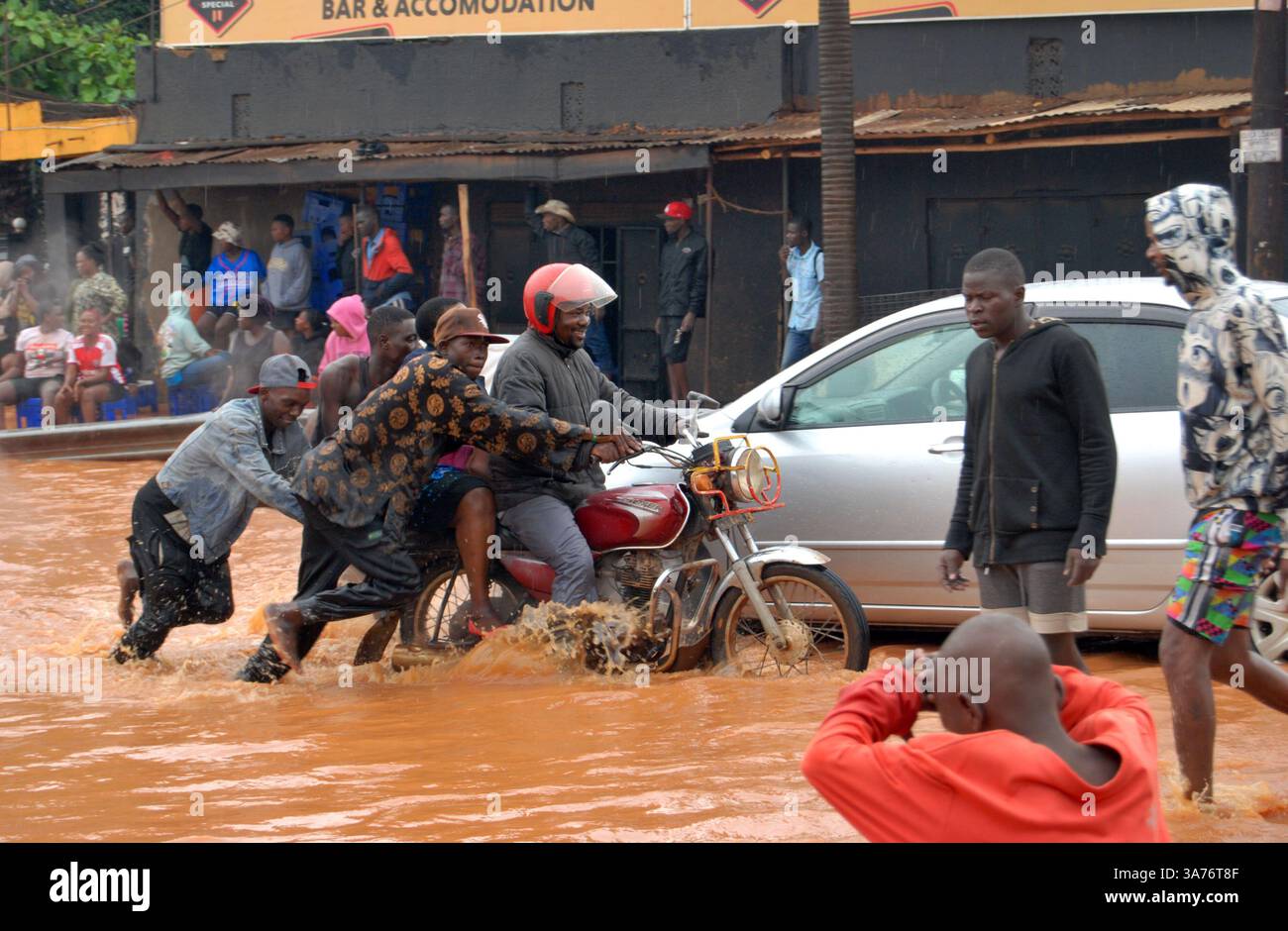 Kampala, Uganda. 26th Mar, 2025. People wade through a flooded road in ...