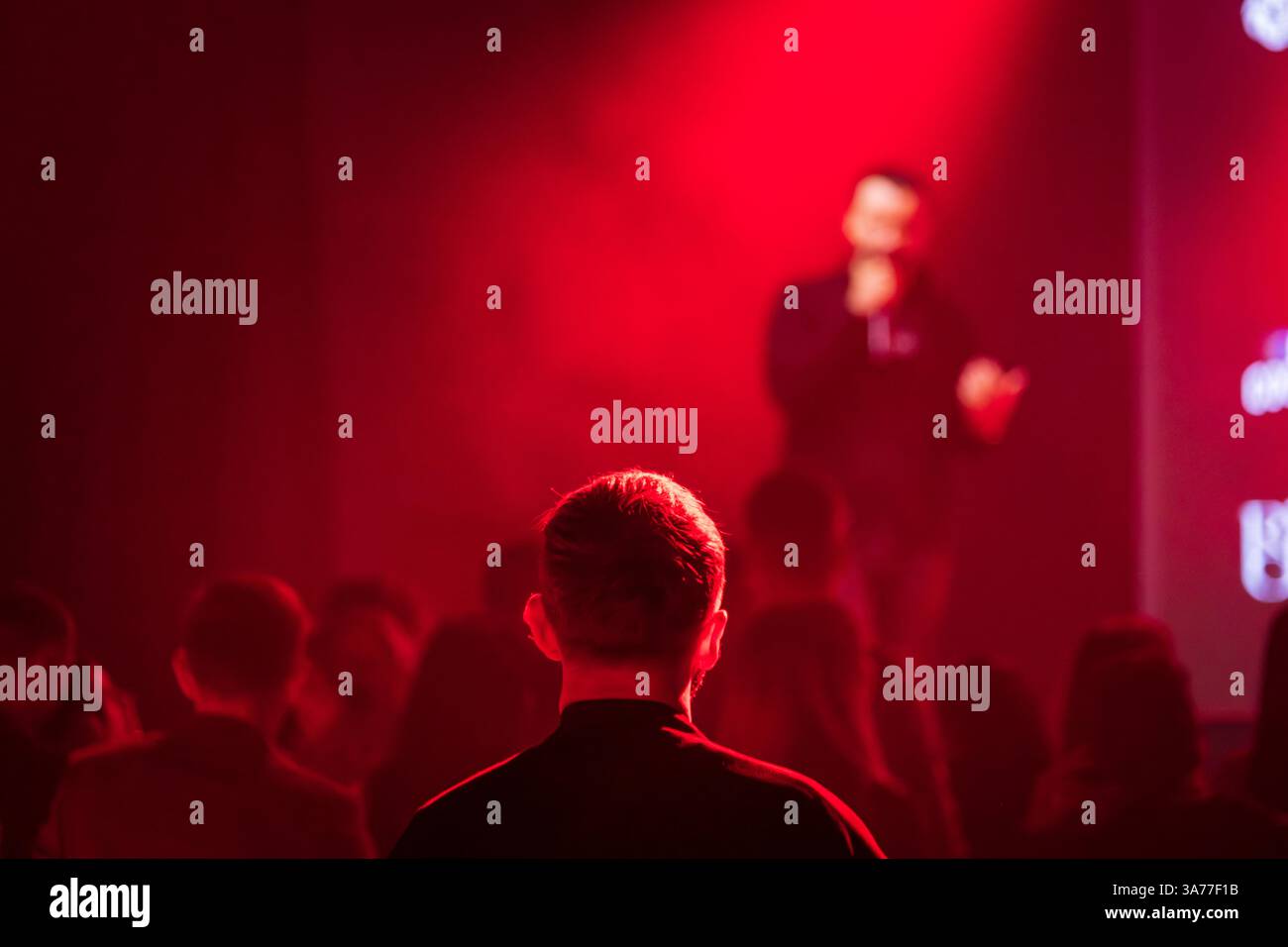 Back view of person in audience at live event with dramatic red ...