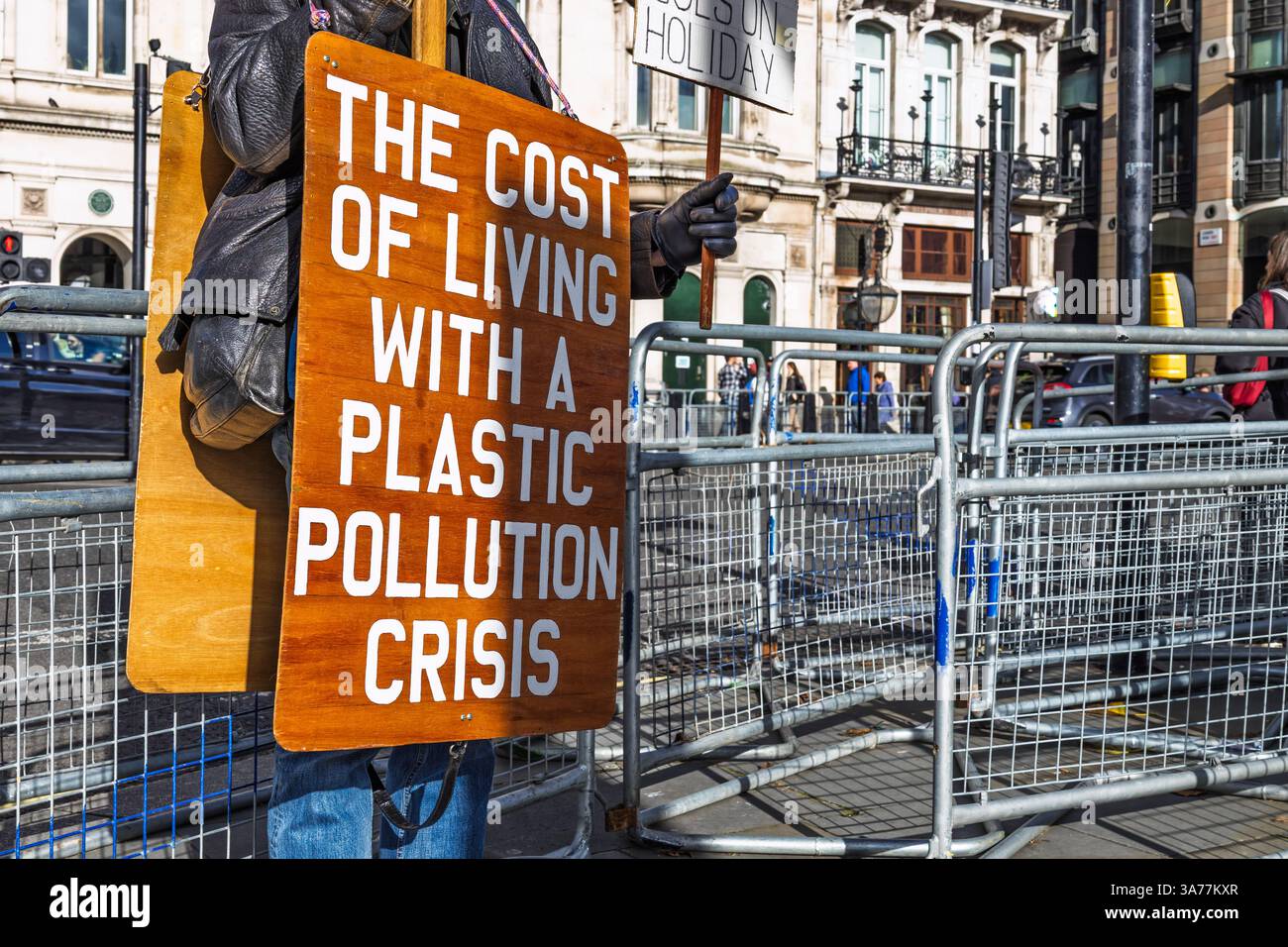 Environmental activist holds sign - plastic pollution and living costs ...
