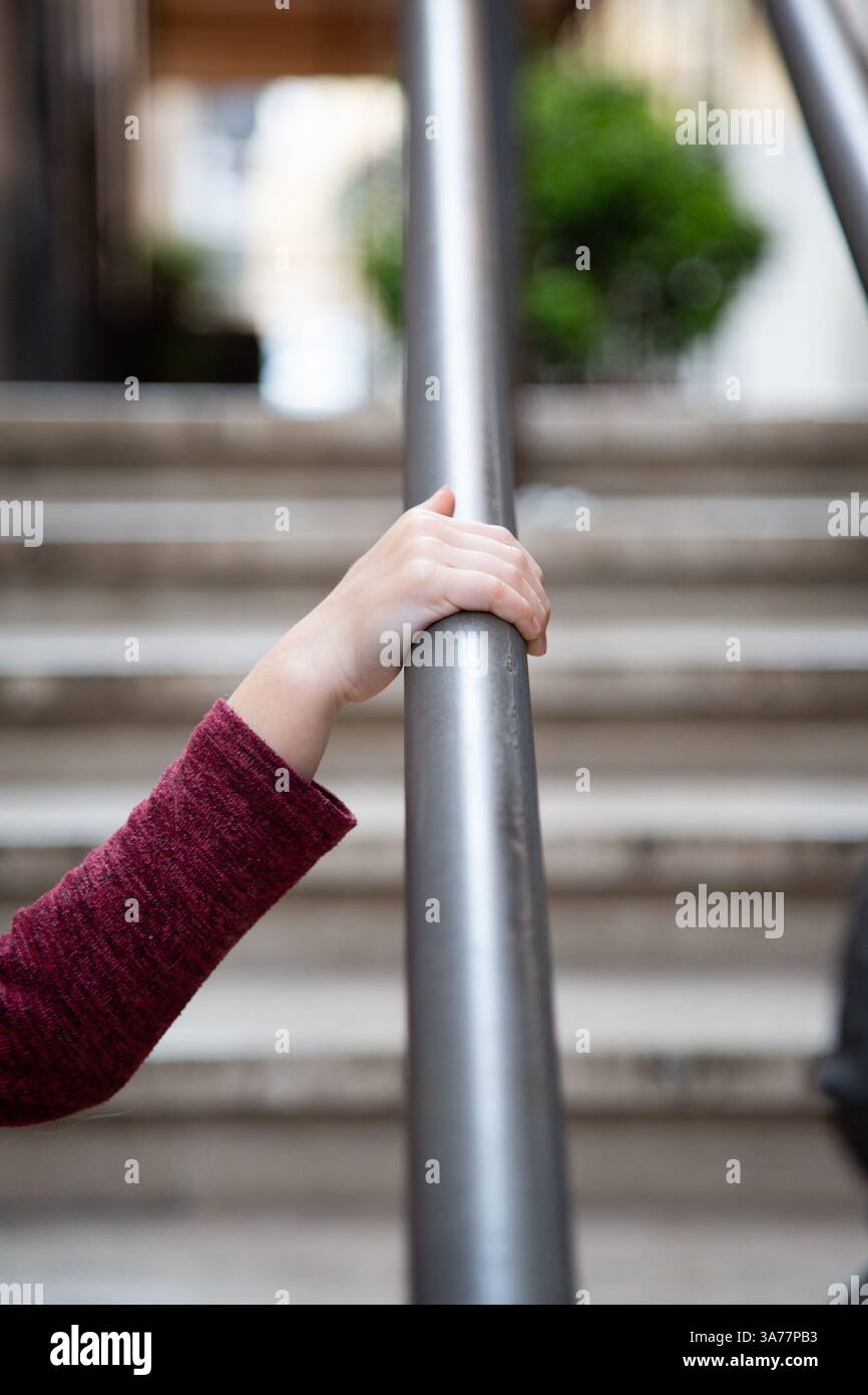 A person is holding onto a metal railing on a set of stairs Stock Photo ...