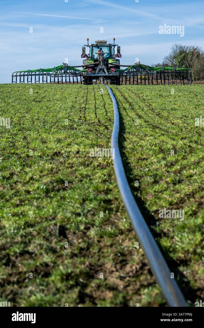Farmer spreads slurry using an umbilical pump system and dribble bar ...