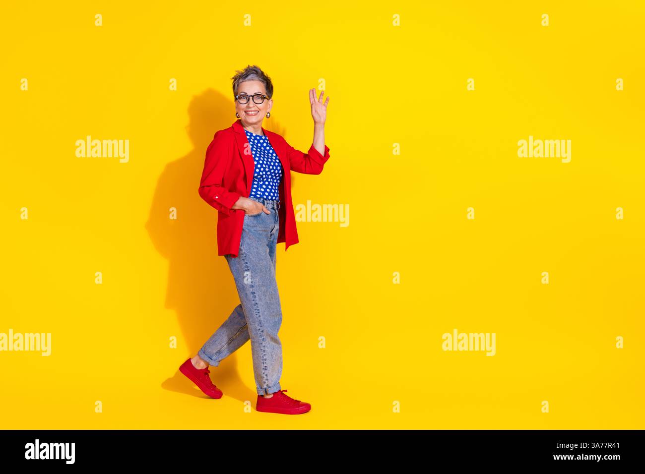 Confident Senior Woman in Stylish Attire Walking Against Bright Yellow ...