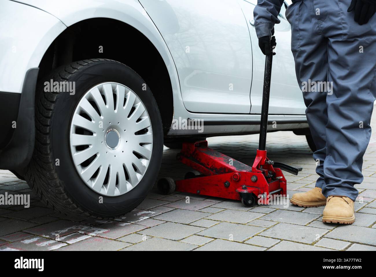 Auto mechanic lifting car with scissor jack outdoors, closeup Stock ...