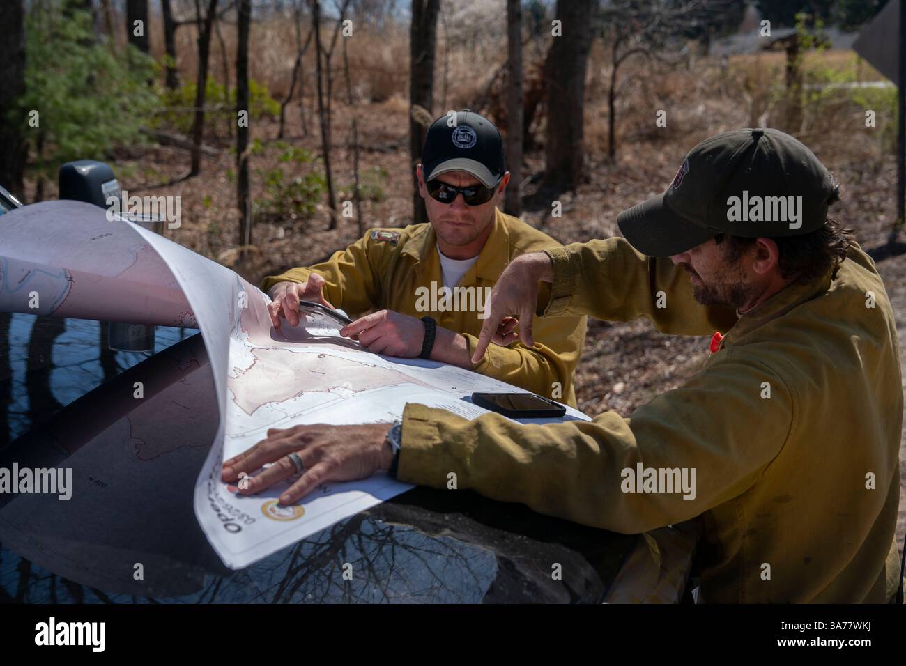 Firefighters look at a map as the Black Cove Fire burns nearby ...