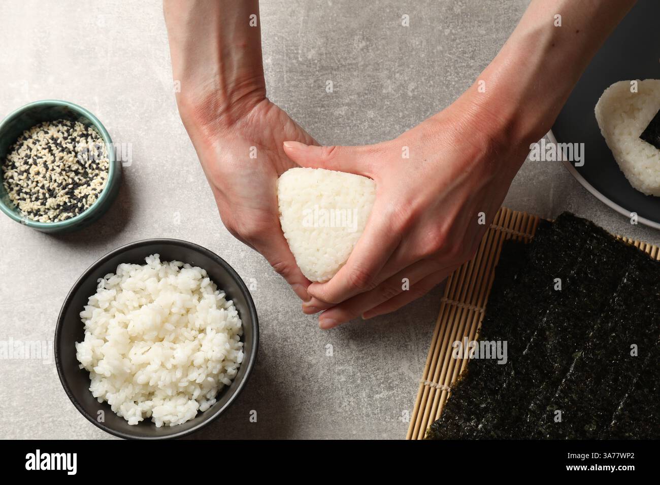 Woman making tasty onigiri (Japanese rice balls) at light table, top ...