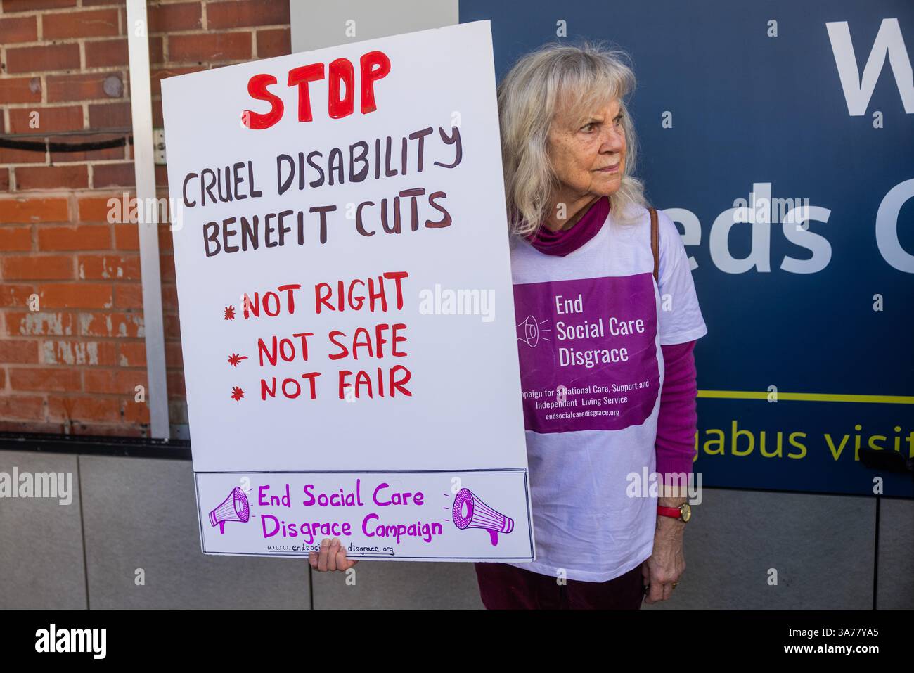 Leeds, UK. 26 MAR, 2025. Person holds "Stop Cruel Disability beneefit ...