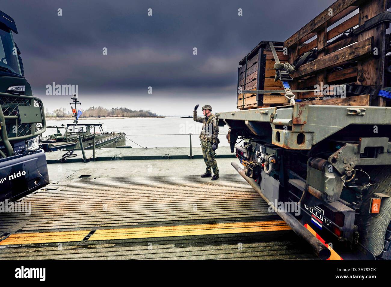 A soldier hand signals to the truck driver as he guides him to the ...