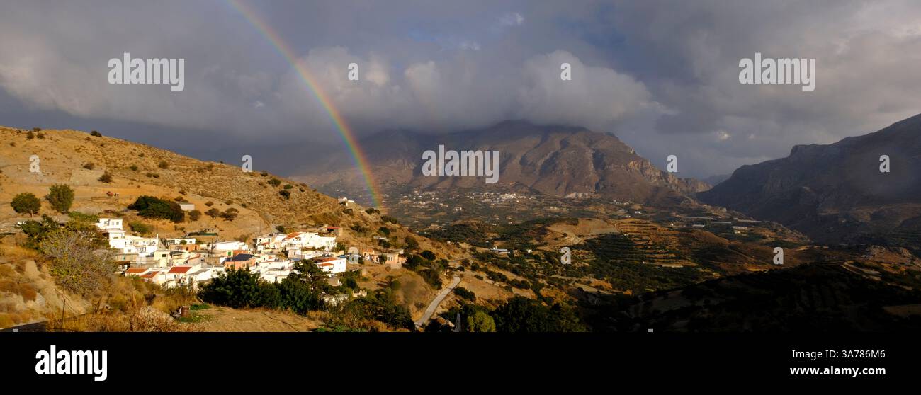 After a brief rain shower, a vibrant rainbow arcs over a small village ...