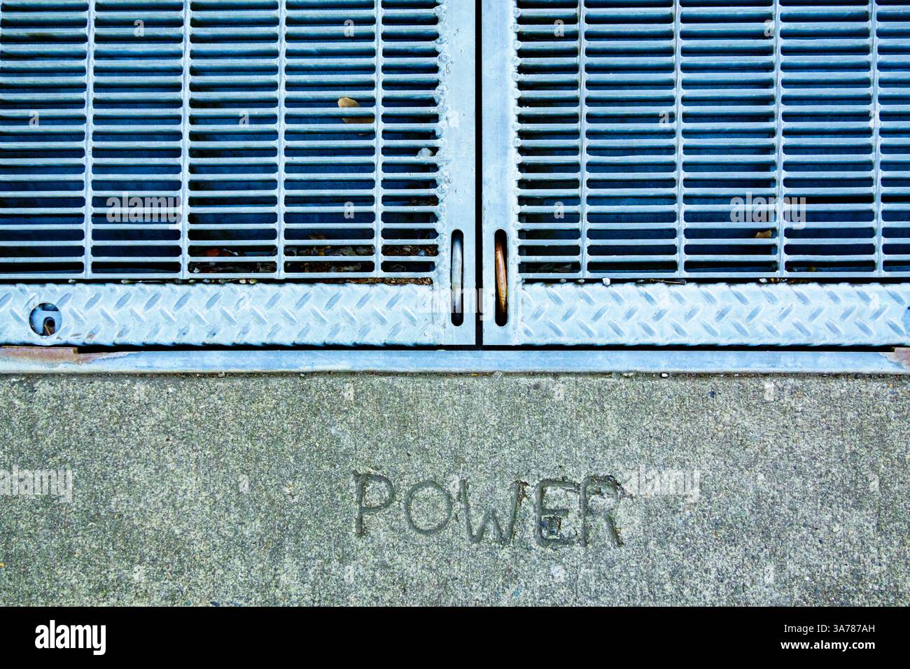 A metal grille over a power utility vault on a wall, the word Power ...
