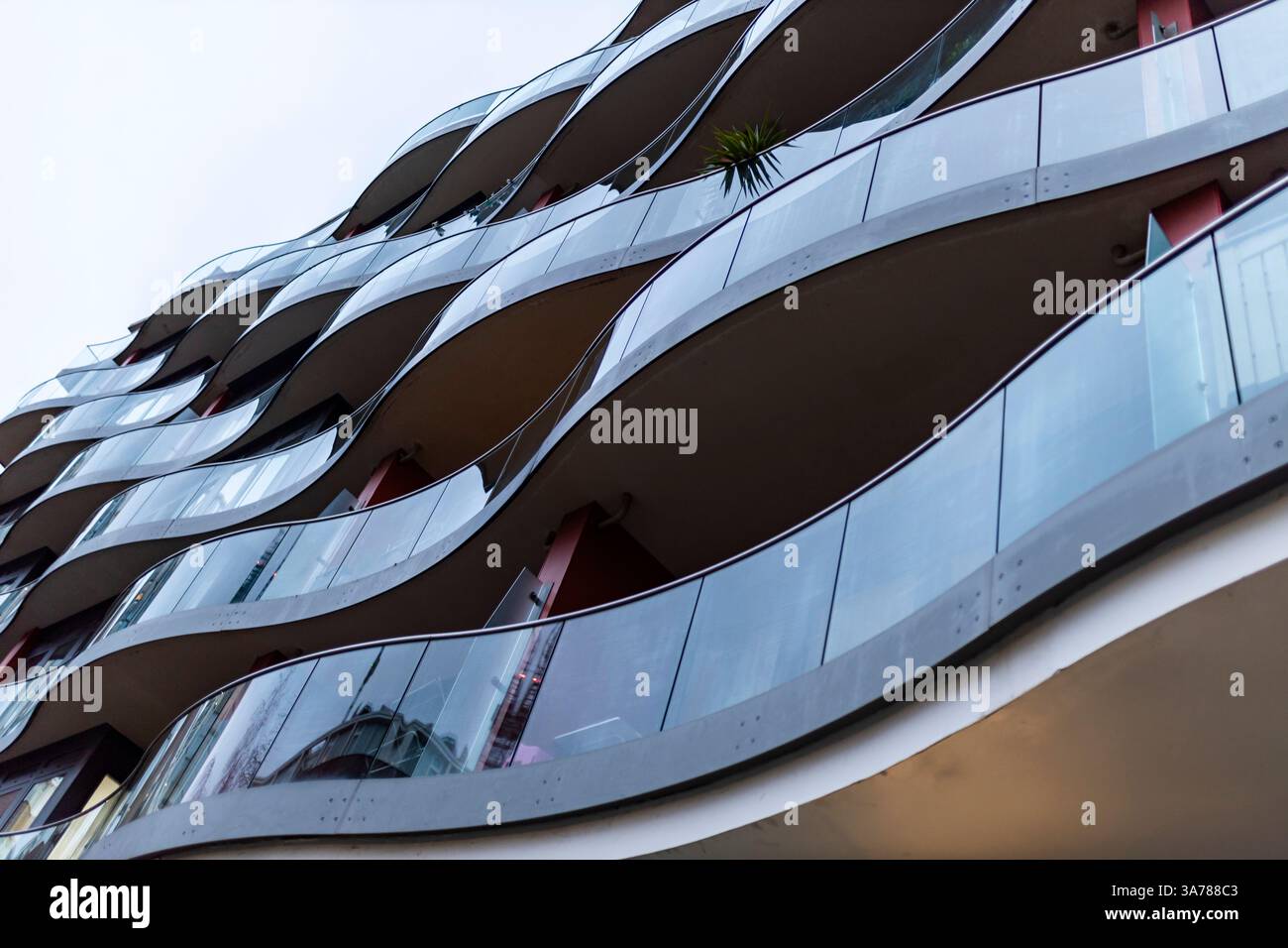 Modern residential building with curved balconies and glass railings ...