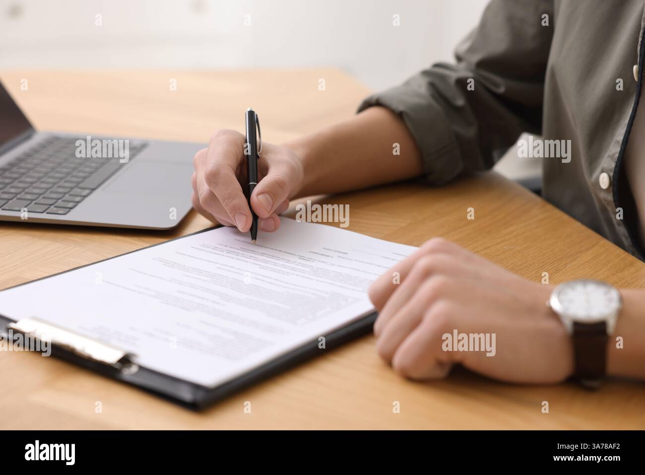 Client signing notarial document at wooden table in office, closeup ...