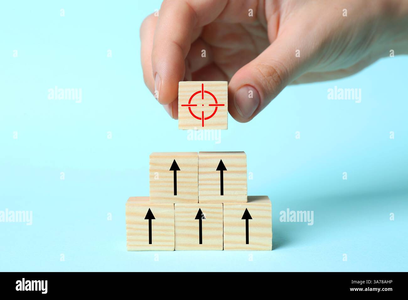 Targeting. Woman putting cube with bullseye on top of pyramid of other ...