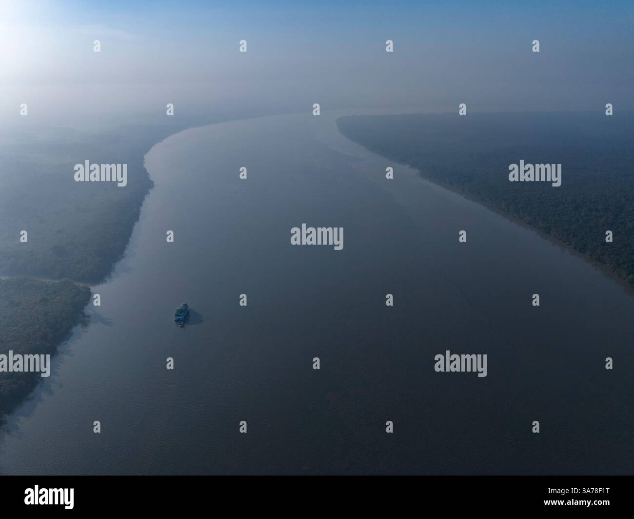 On a foggy winter morning, a tourist vessel is anchored on a river near ...