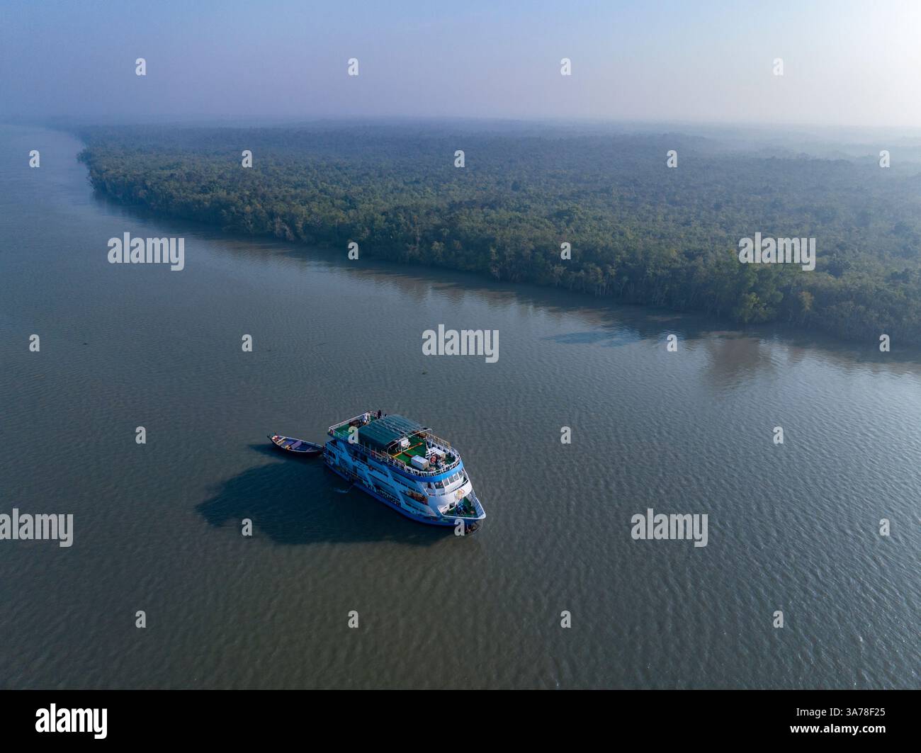 On a foggy winter morning, a tourist vessel is anchored on a river near ...