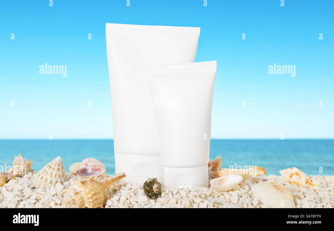 Tubes of sunscreen products and seashells on beach near ocean Stock ...