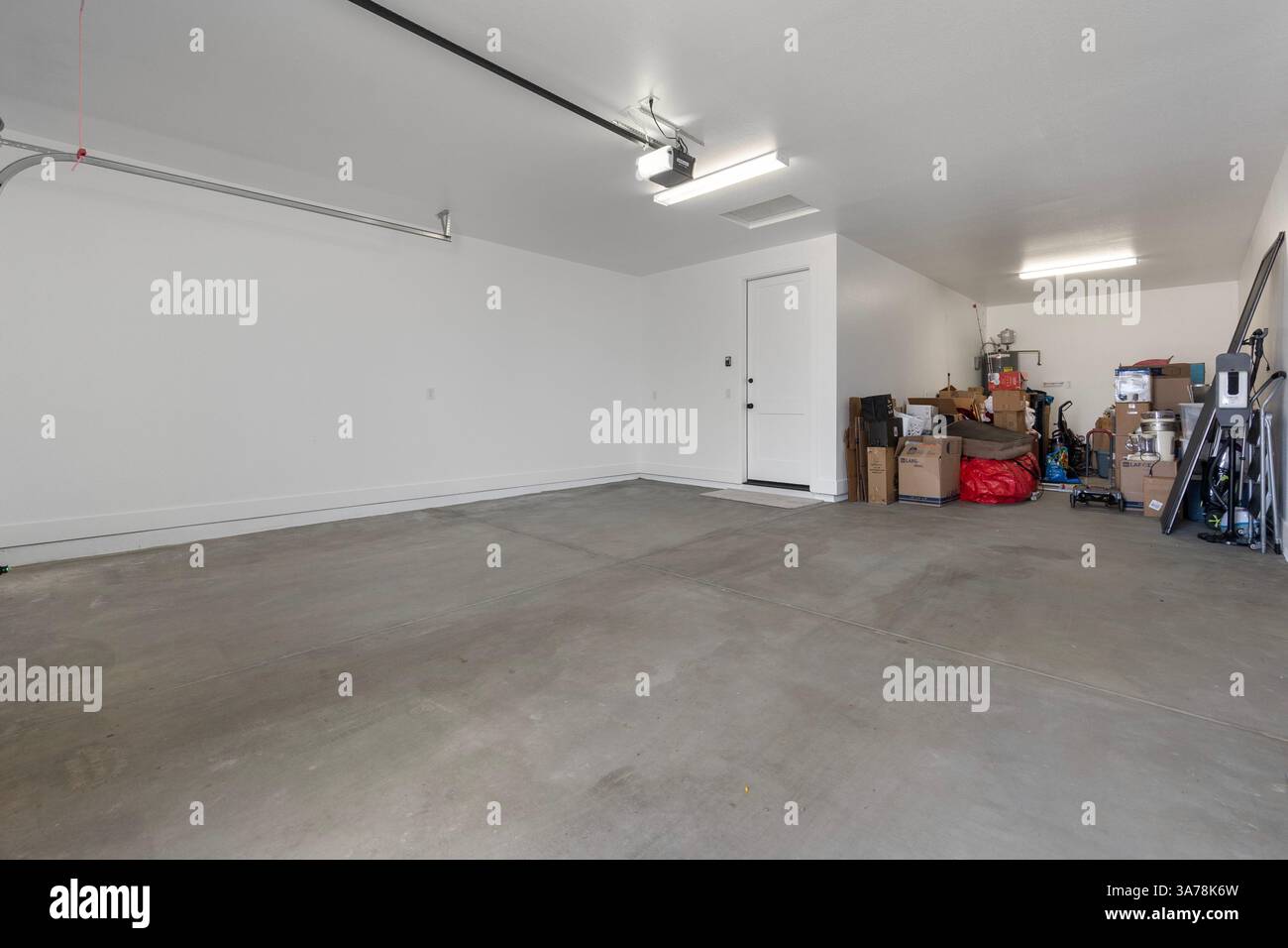 Inside an empty garage, the garage door is wide open, revealing a ...