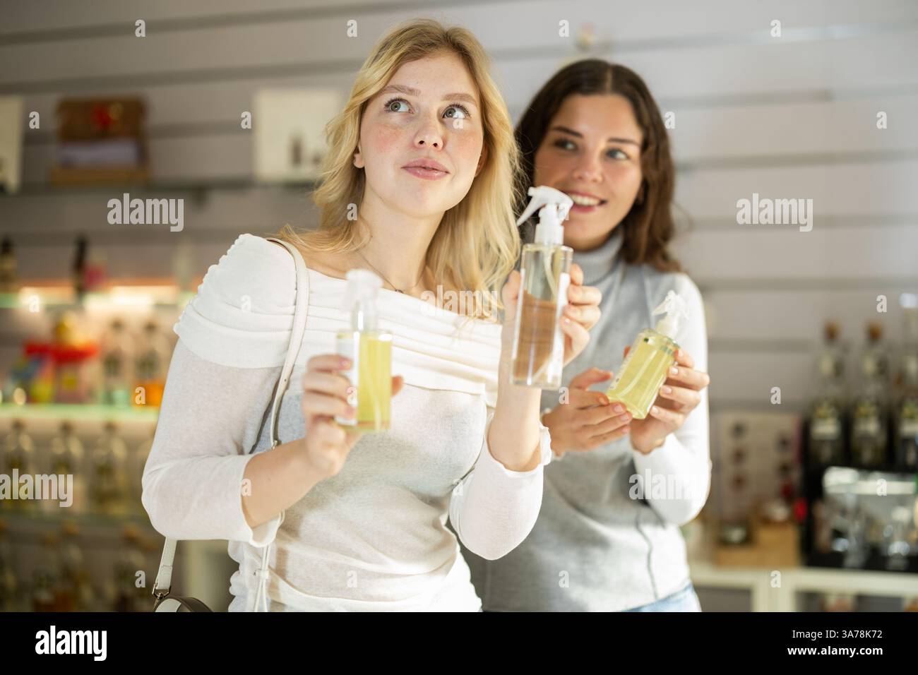 Two girlfriends choose aromatic perfumes together in perfume shop Stock ...