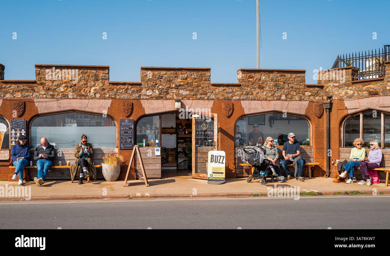 People sitting outside a Sidmouth seafront cafe on a sunny day in early ...