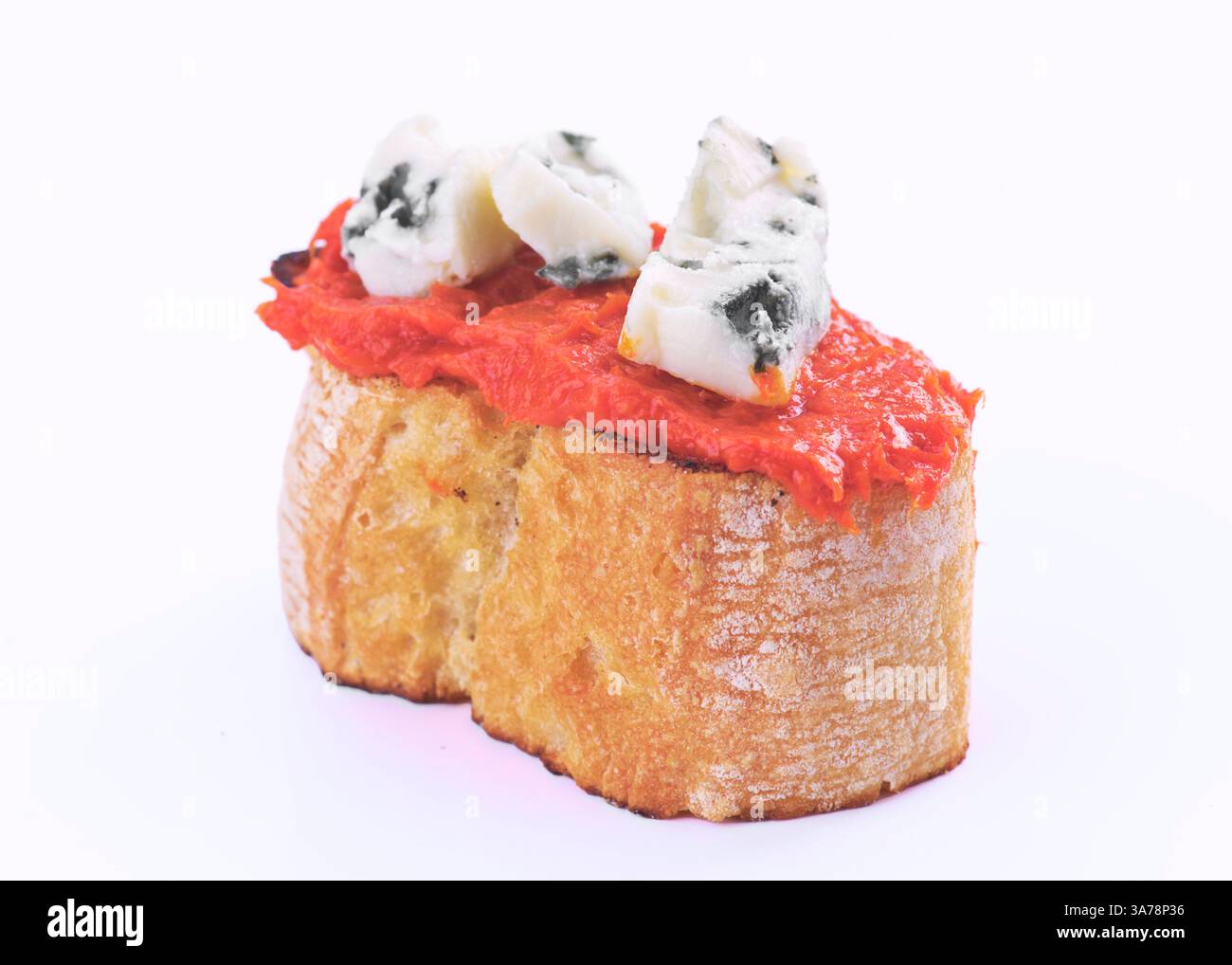 Toasted baguette slice topped with roasted red pepper paste and blue ...