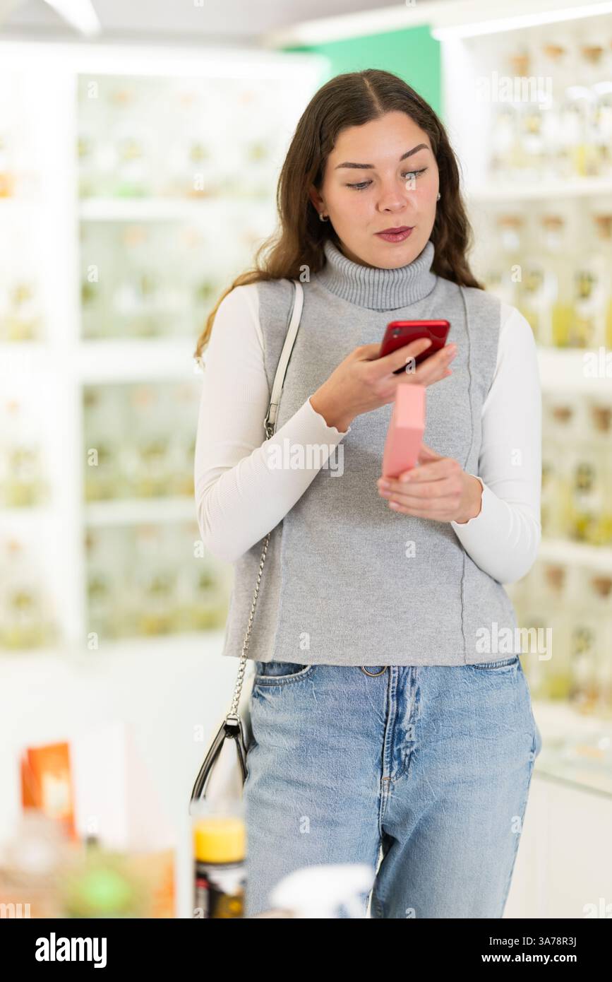 Female shopper scanning QR code on perfume in perfume shop Stock Photo ...