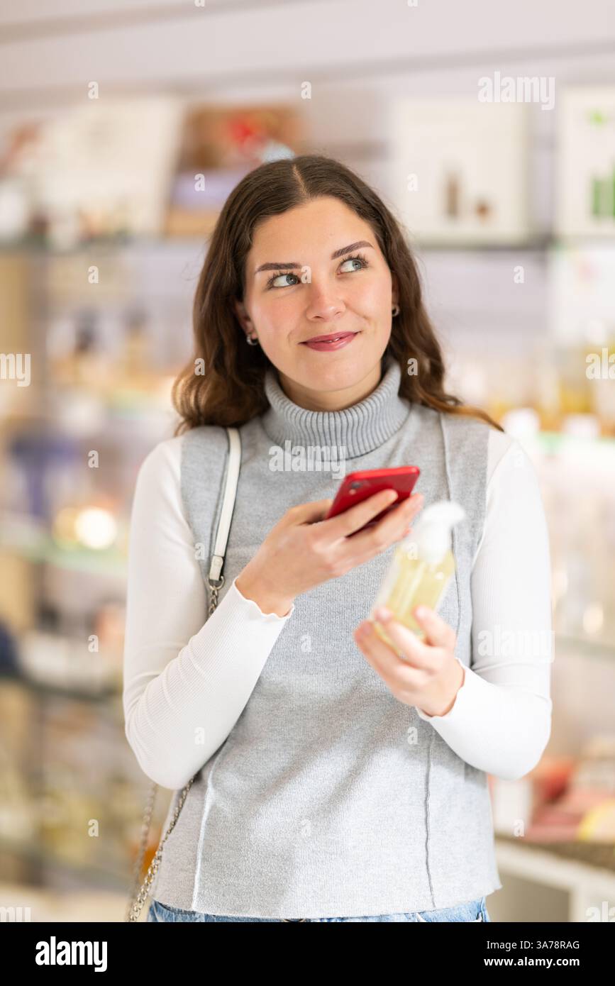 Female shopper scanning QR code on perfume in perfume shop Stock Photo ...
