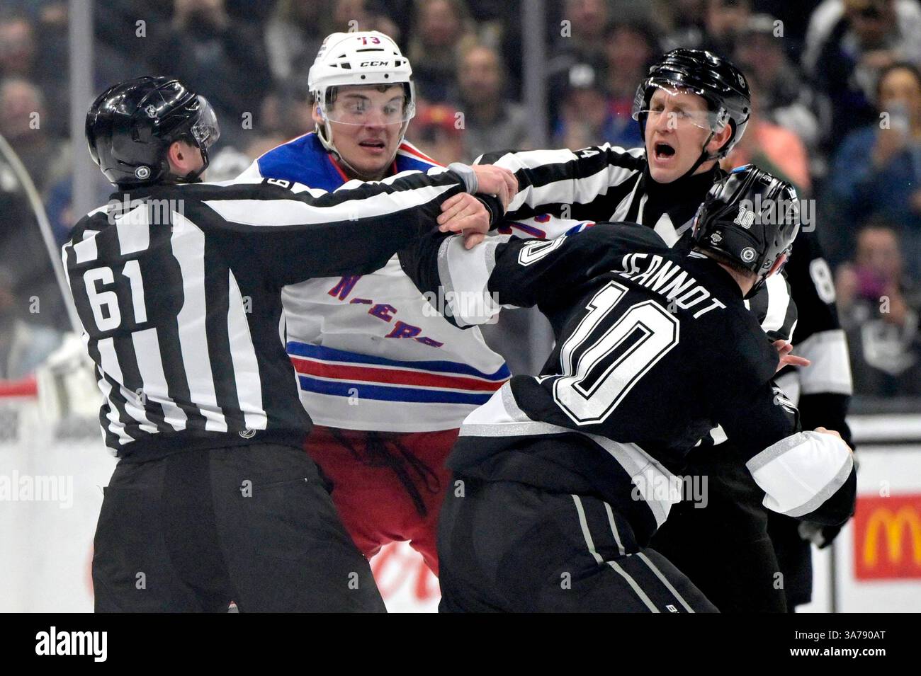 Linesman James Tobias (61) and referee Trevor Hanson reach in to stop a ...