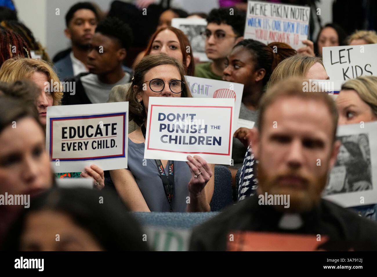 People hold signs during a House Education Committee hearing Wednesday ...