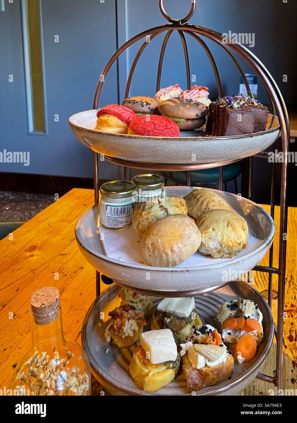 Tiered afternoon tea stand with sweet and savory treats in a cozy café ...