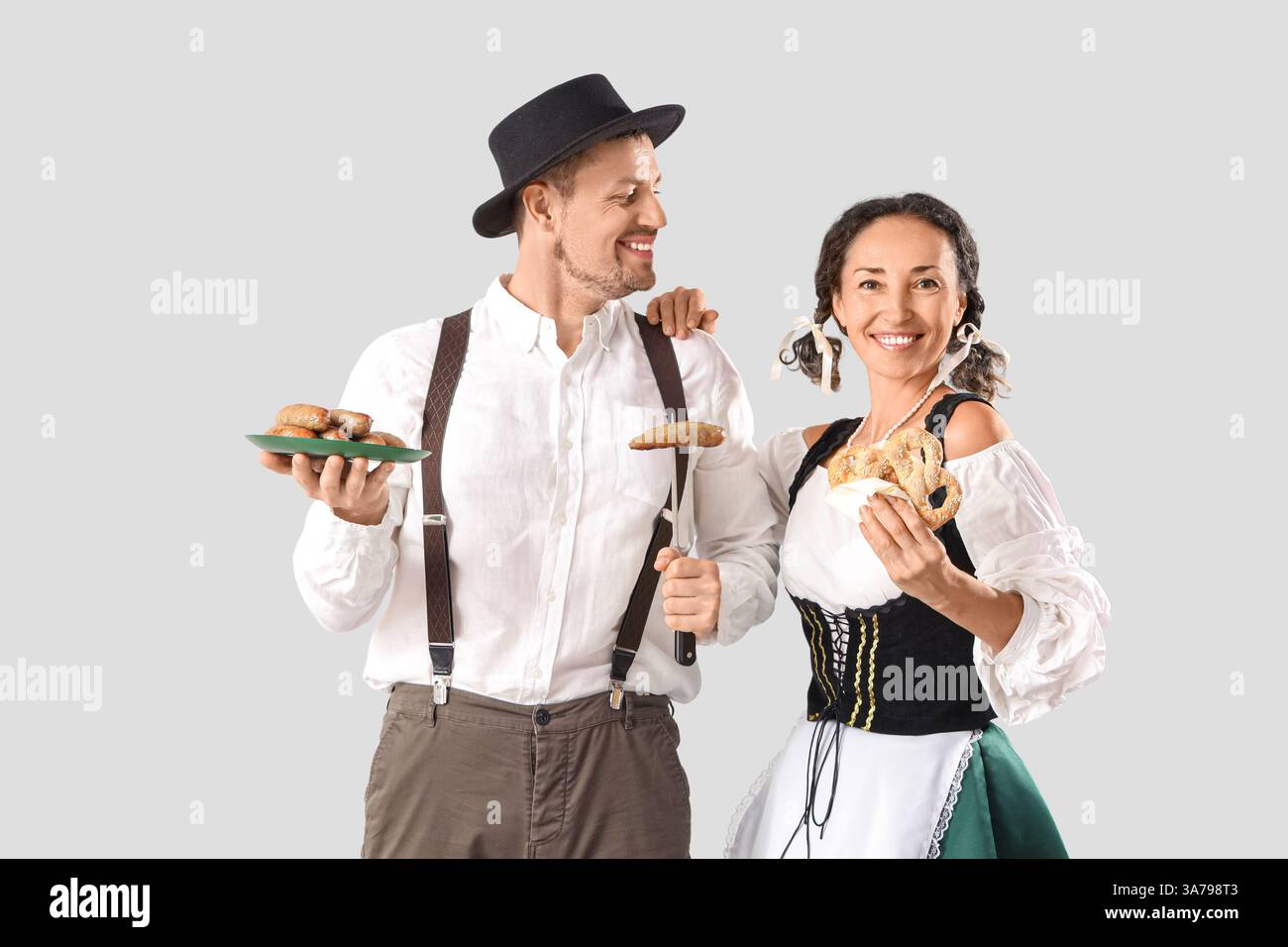 Happy mature waiters in traditional German clothes with sausages and ...