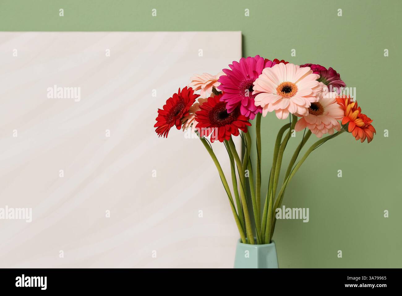 Beautiful gerberas in vase and picture near green wall in room Stock ...