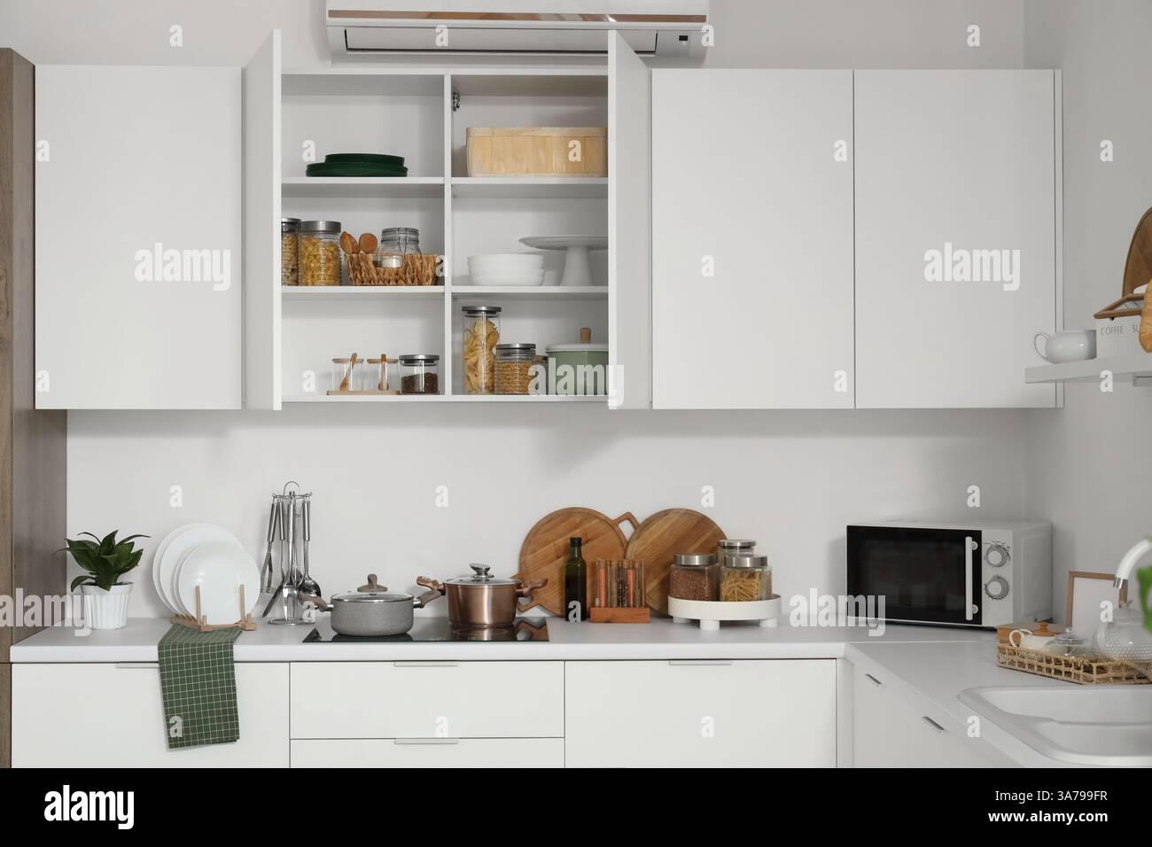 Open cupboard with utensils in light kitchen interior Stock Photo - Alamy