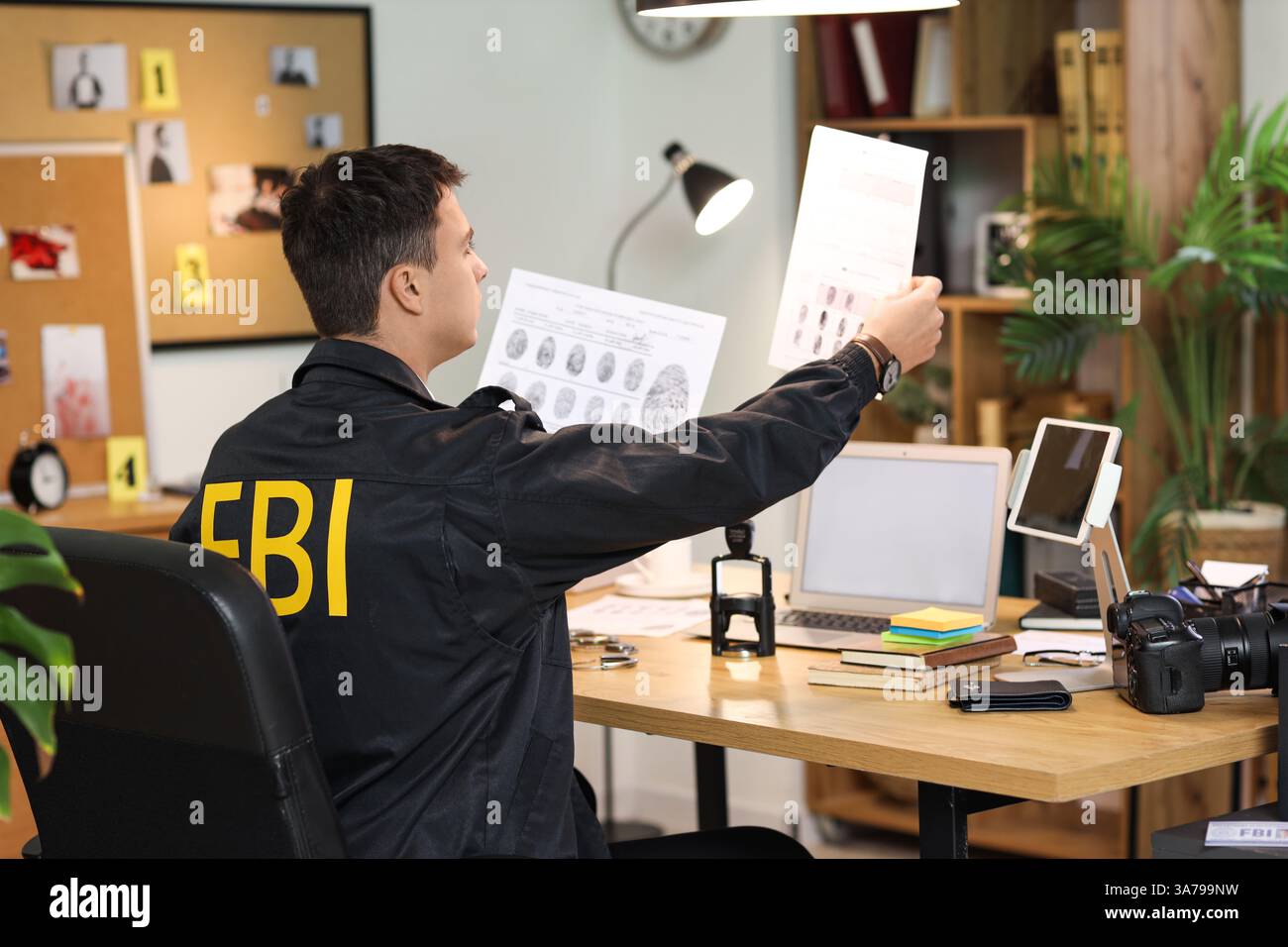 Male FBI agent studying fingerprints at table in office, back view Stock Photo - Alamy