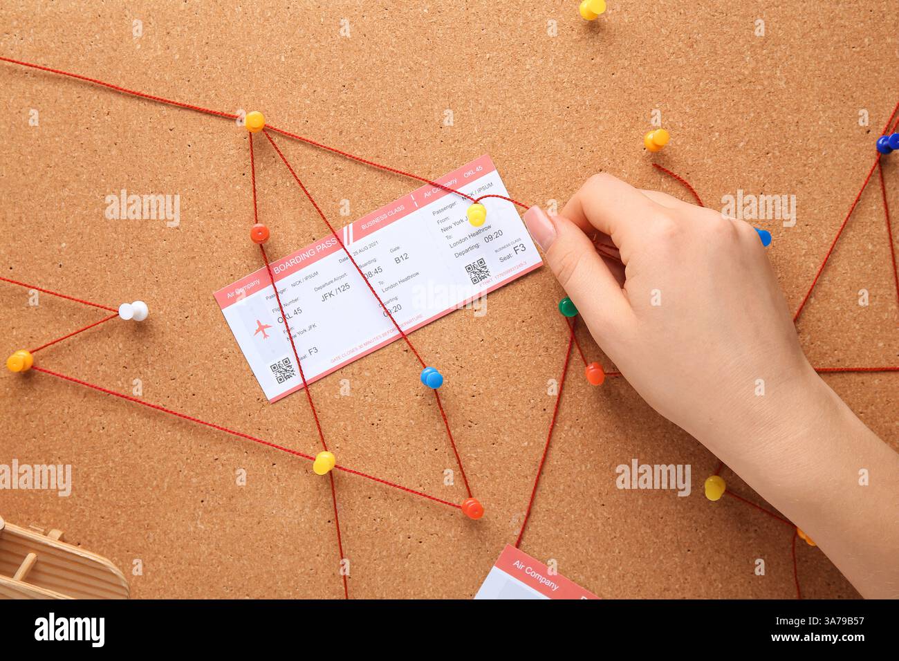 Female hand and thread, pins and ticket on board, closeup. Itinerary ...