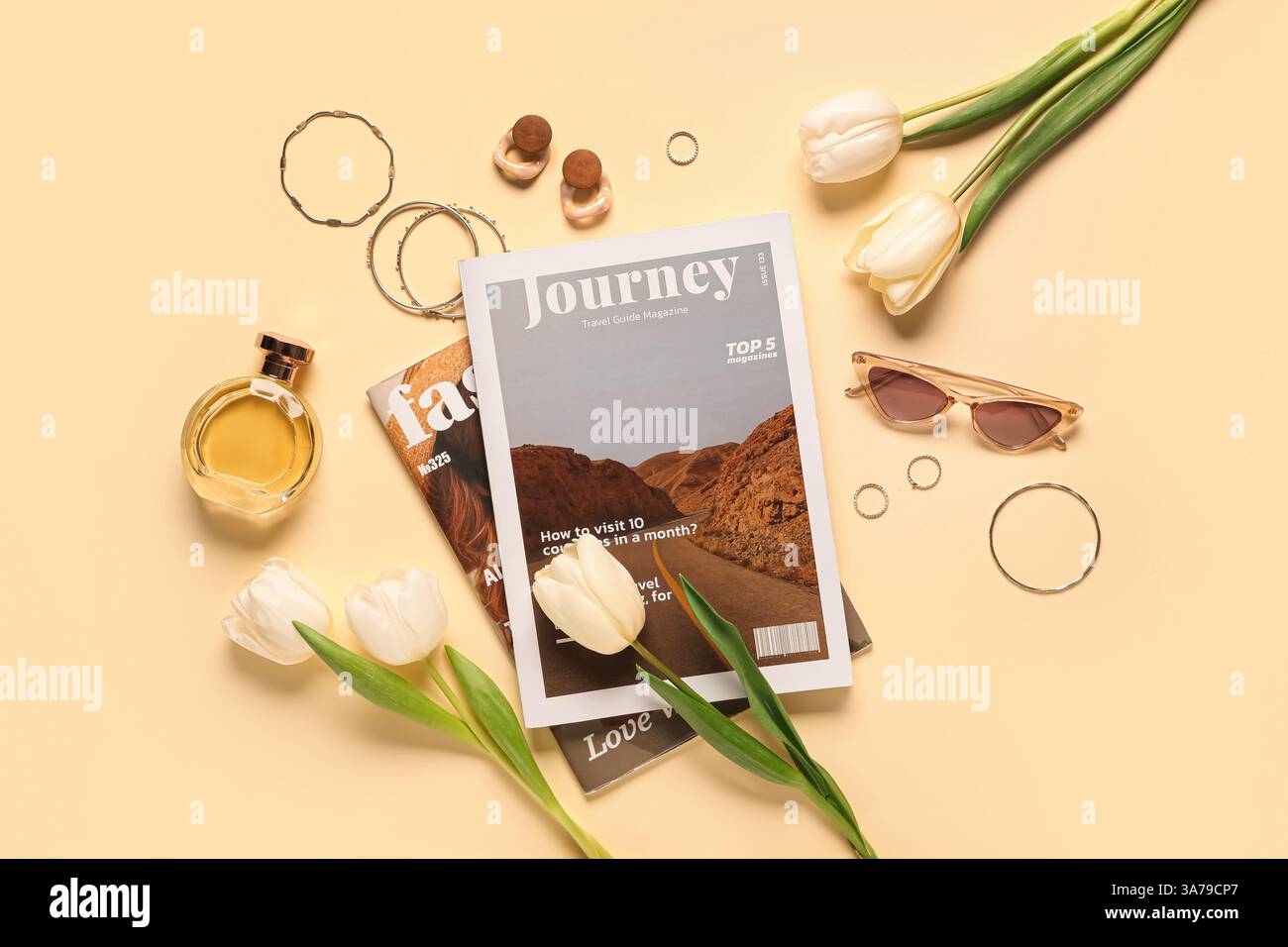 Fashion magazine with flowers, perfume and jewellery on yellow ...