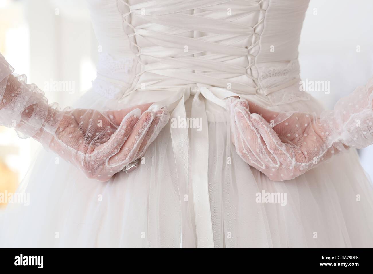Beautiful bride tying corset in bedroom, back view Stock Photo - Alamy